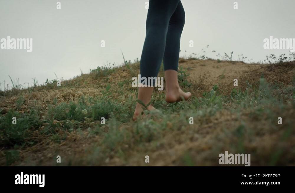 Barefoot girl climbing green hill close up. Young lady feet walking ...