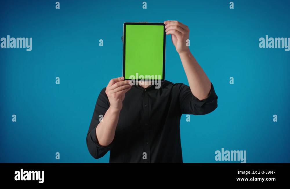 Portrait handsome European guy hiding face by vertical tablet pc green ...