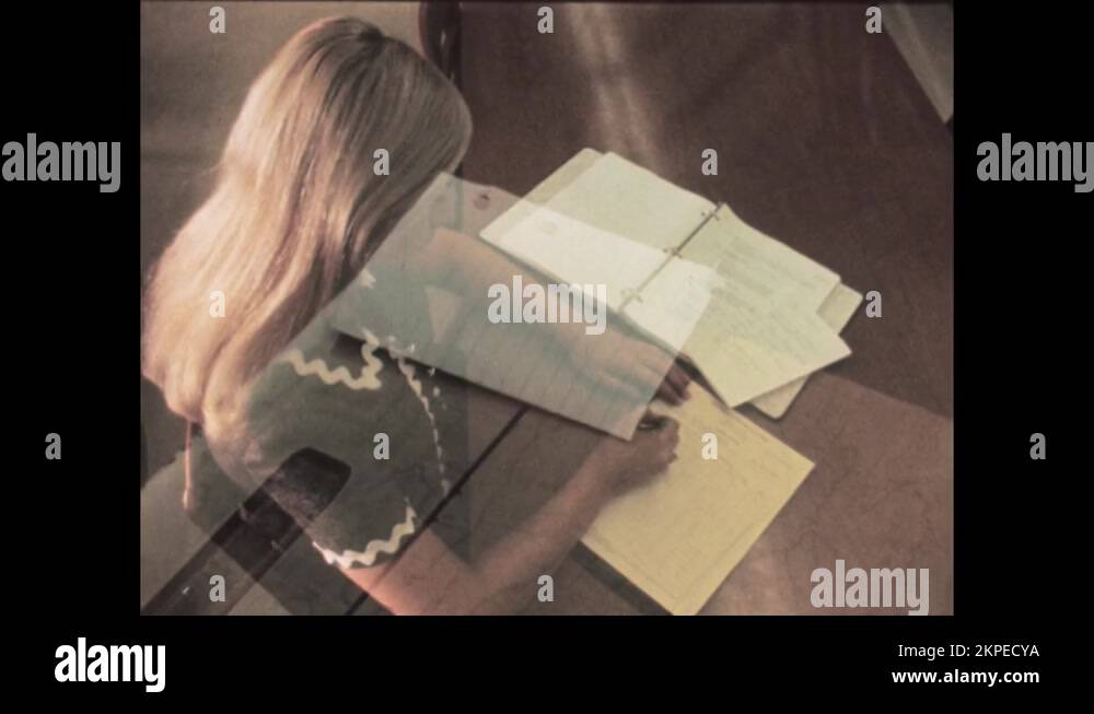 1970s: boy puts note on school desk. Lady marks homework. Lady hands in ...