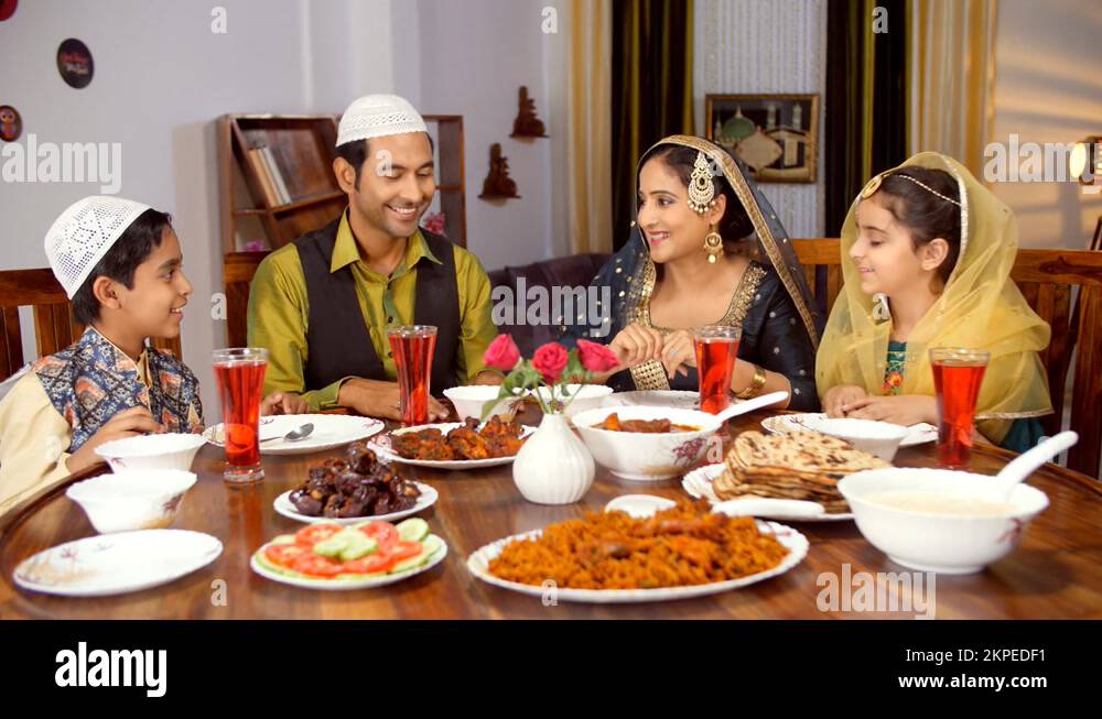A happy Muslim family offering prayers before Eid - dining table, food ...