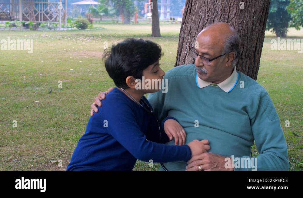 A young schoolboy playing with his grand father - acting as a doctor ...