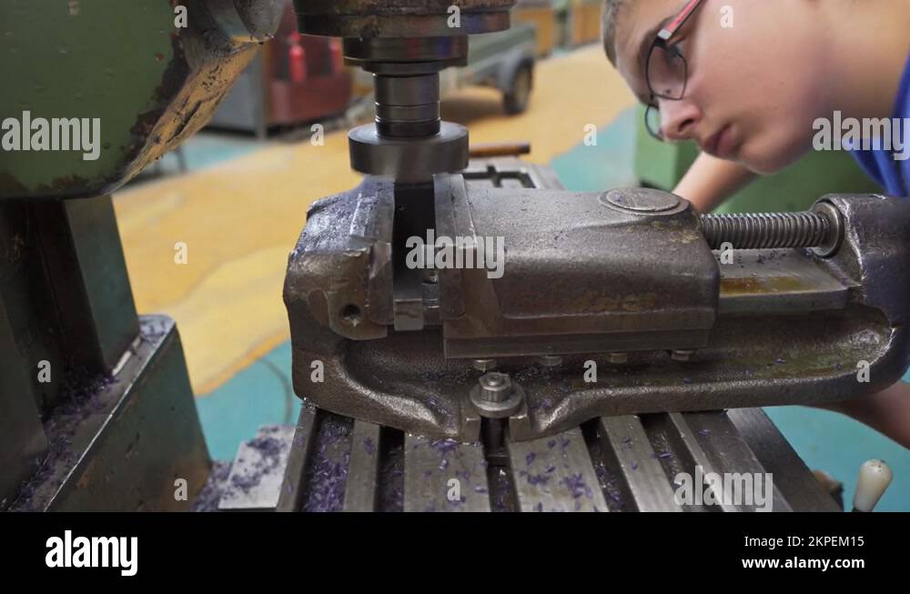 Young male student intently practising how to use a metal lathe at a ...