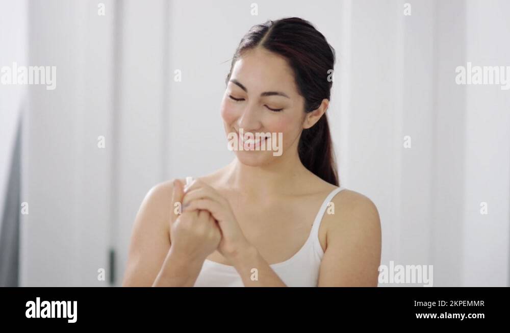 Pretty young woman rubs smooth hands together while admiring herself in ...