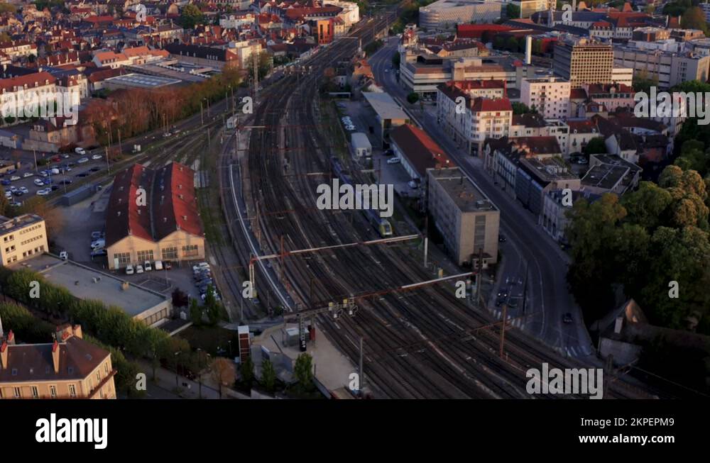 Europe train entering city on tracks drone follow shot at golden hour ...