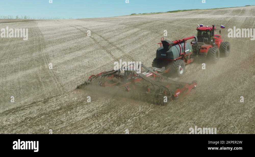 Tractor sowing seeds with seeder driller in field. Process of sowing ...