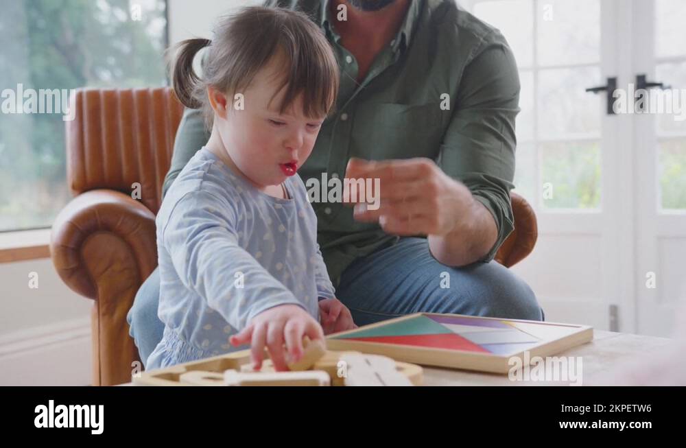 Father With Down Syndrome Daughter Playing Game With Wooden Shapes At ...