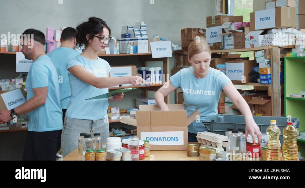 Teamwork of food bank workers packing donation boxes with provision ...