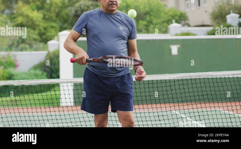 Video of happy biracial senior man holding racket and tossing ball on ...