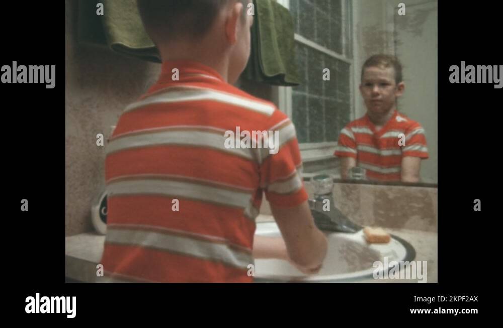 1960s: Slate. Boy washes his hands at the bathroom sink. Slate. Boy ...