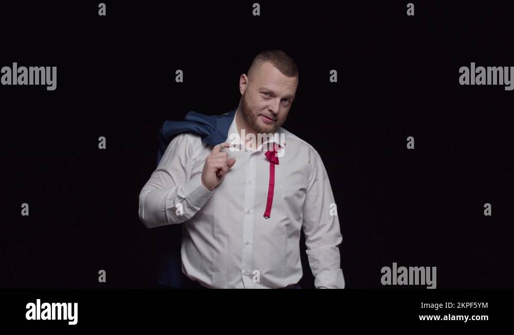A man with a beard in a white shirt with a red bow tie unbuttoned and a ...