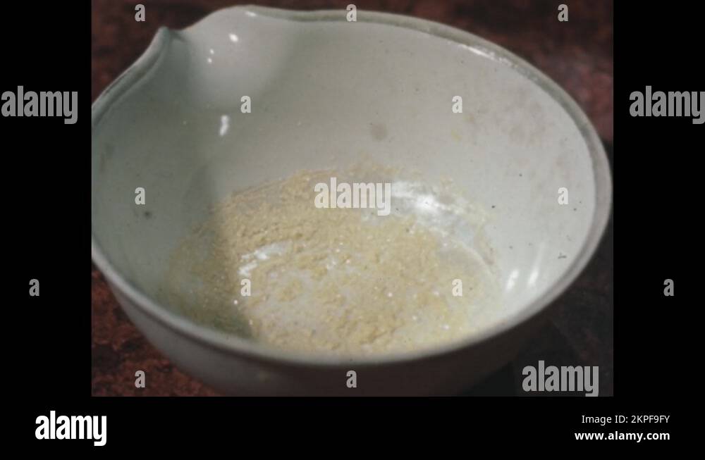 1940s: Chemist points to sulfur crystals in bowl under funnel. Man ...