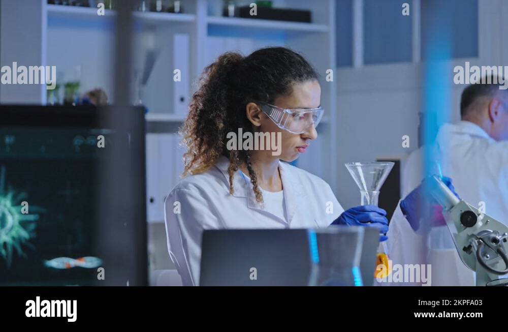 Female lab assistant adding reagent to liquid, observing chemical ...