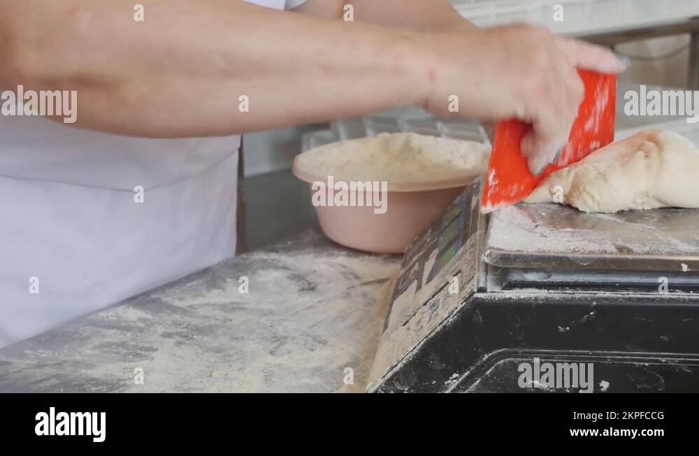 the process of making bread in a bakery. Weighing raw dough on a scale ...