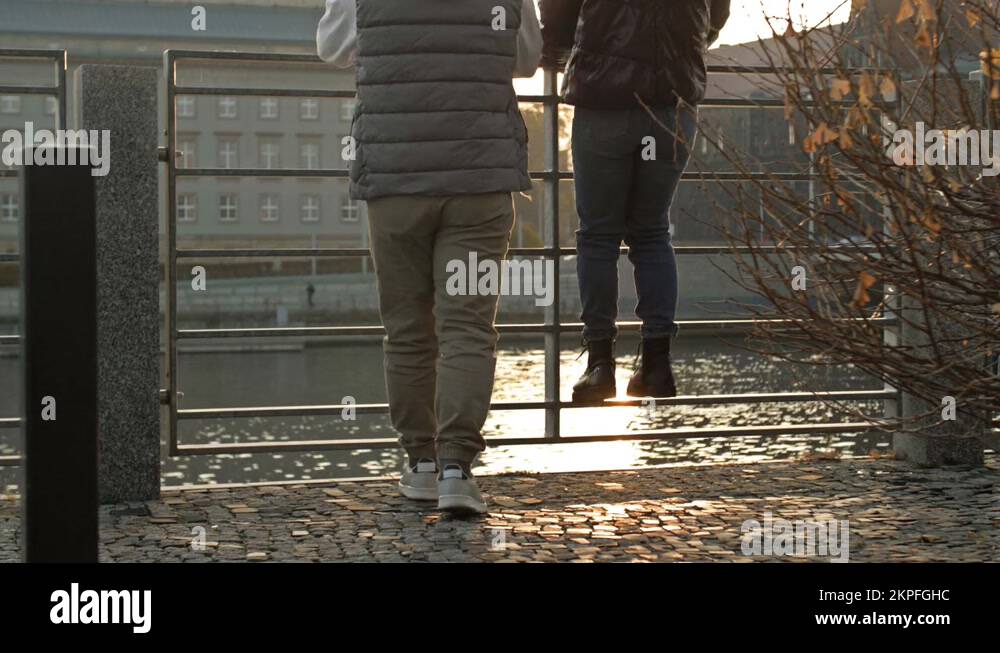 The guy and the girl approached the metal railing on the embankment to ...