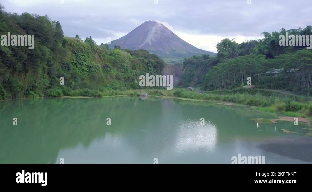 Blue lake surface with Mount Merapi in the background. Bego Pendem is ...