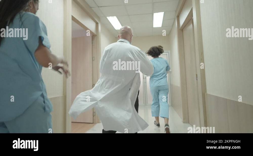 Back view. Doctor or surgeon and nurse running with hurry up into ...