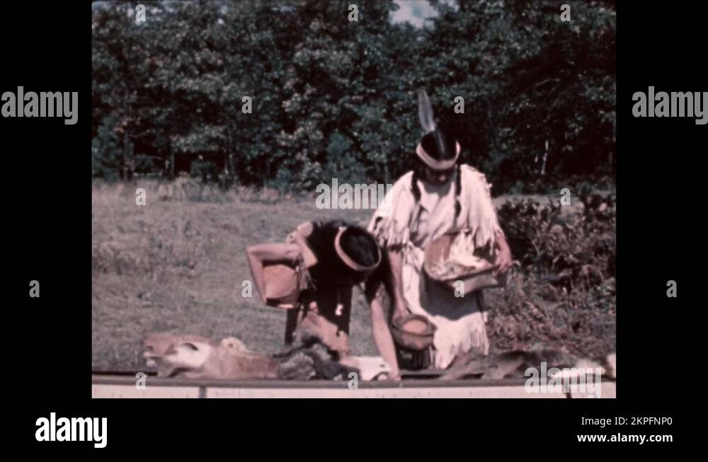 1950s: Native American women take items from canoe. Man picks up bow ...