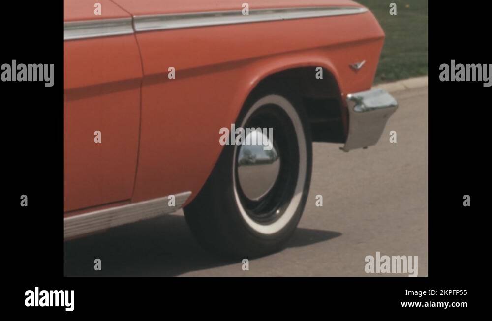 1950s: hub cap on moving wheel of car. Red car panels from side. Old ...