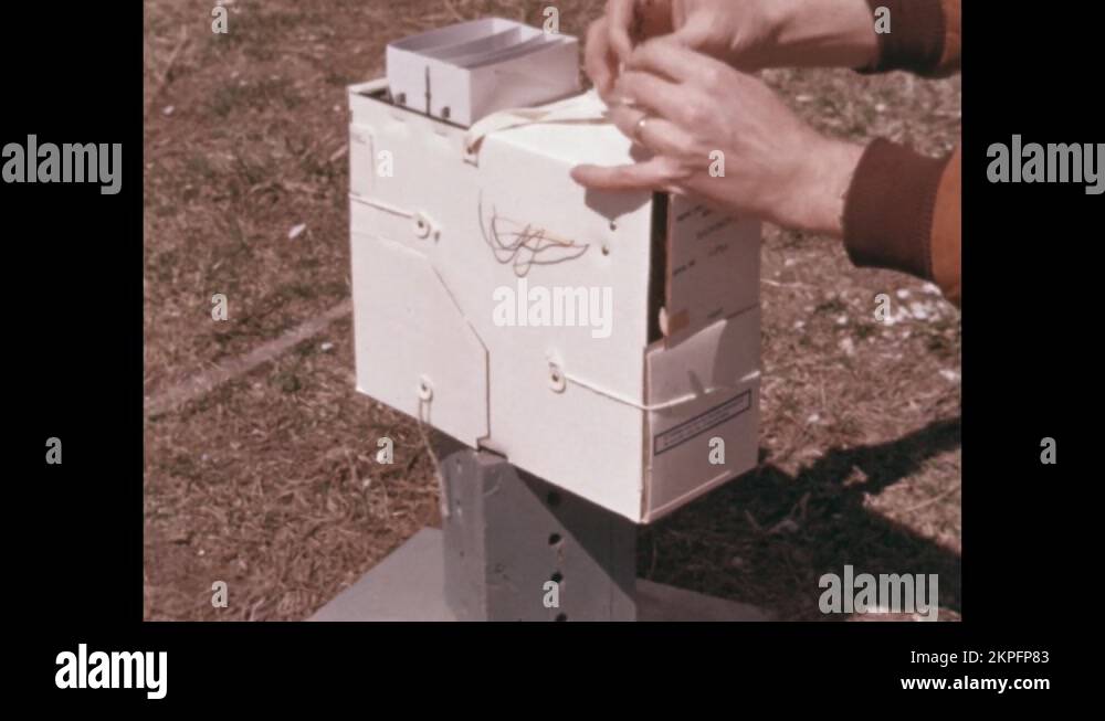 1960s: Person places box with science equipment on pole in ground ...