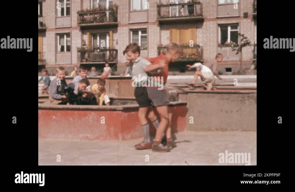 1960s: Children play in courtyard. People in political meeting unfold ...