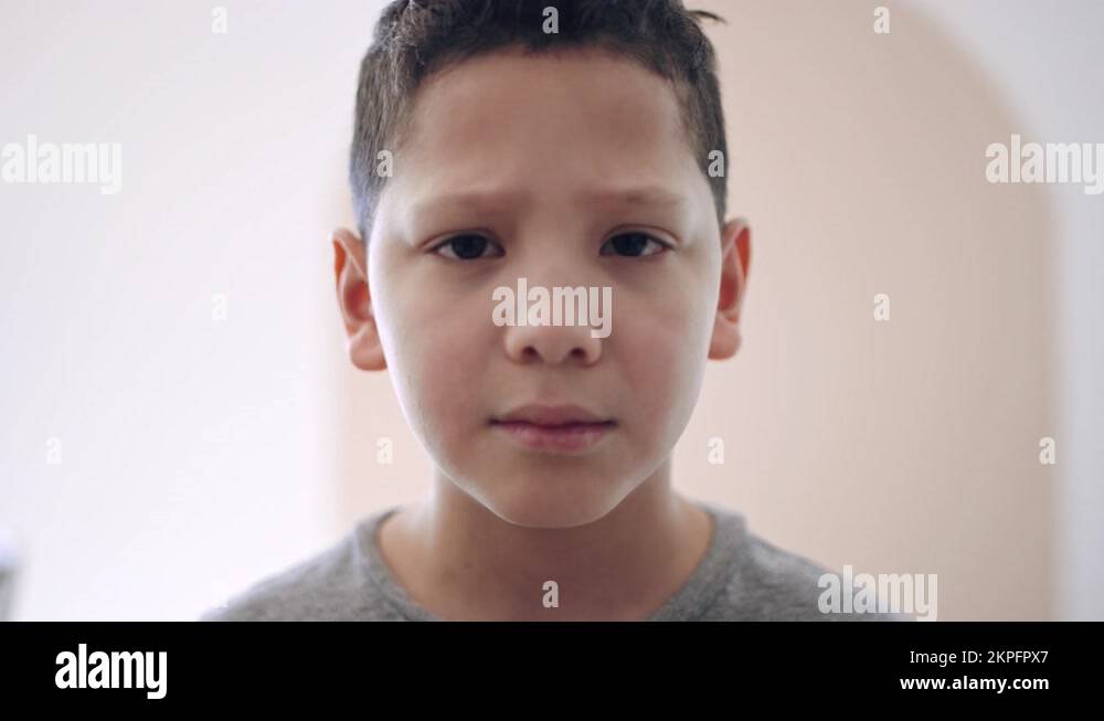 Young biracial boy looks into camera with sad, devastated, crying ...