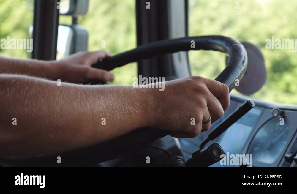 Male hands of lorry driver holds a big steering wheel while driving a ...