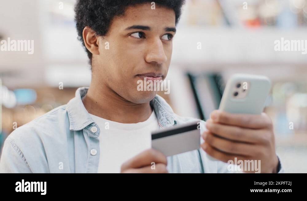 African Dominican guy 20s man holding phone and credit card successful ...