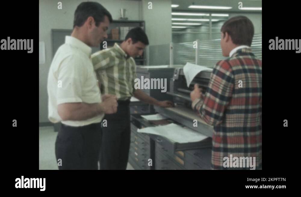 1960s: Three men stand together in office, have a conversation. Two men ...