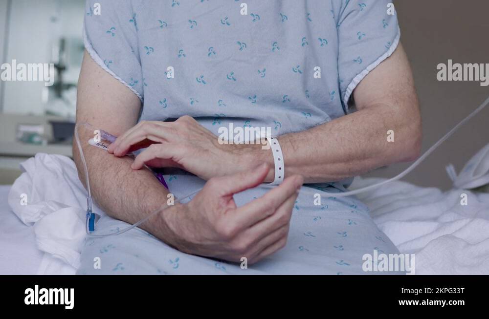 man sitting on his hospital bed adjusting IV tubes Stock Video Footage ...