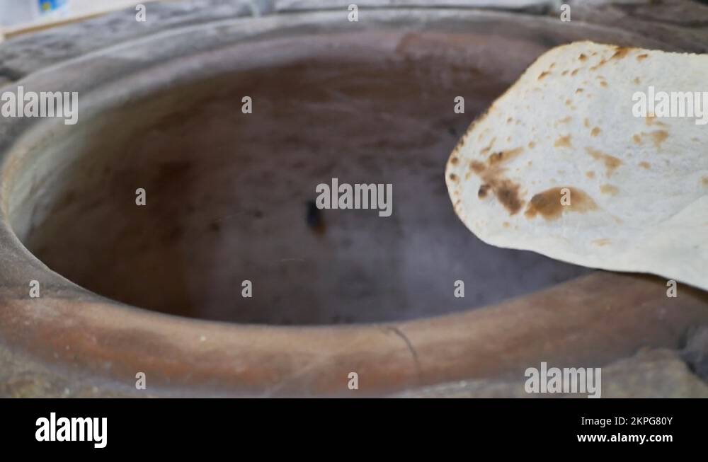 the baker takes out the Armenian lavash baked in the tandoor tonir with ...