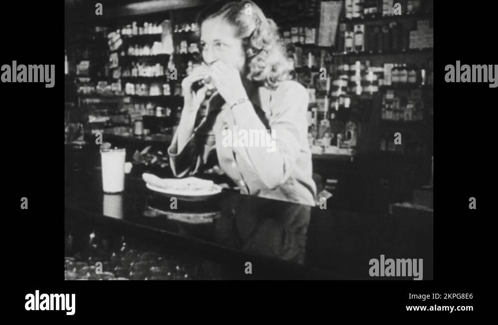 1940s: Attractive woman sits at drug store counter, eats sandwich ...