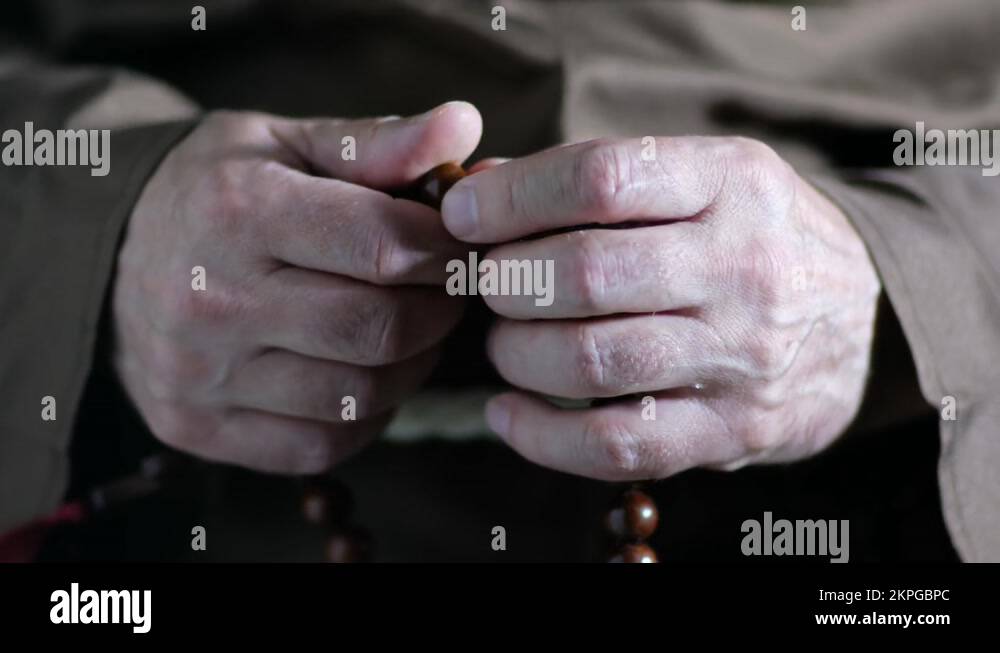 Close up video of the hands of a old monk are fingering the rosary ...