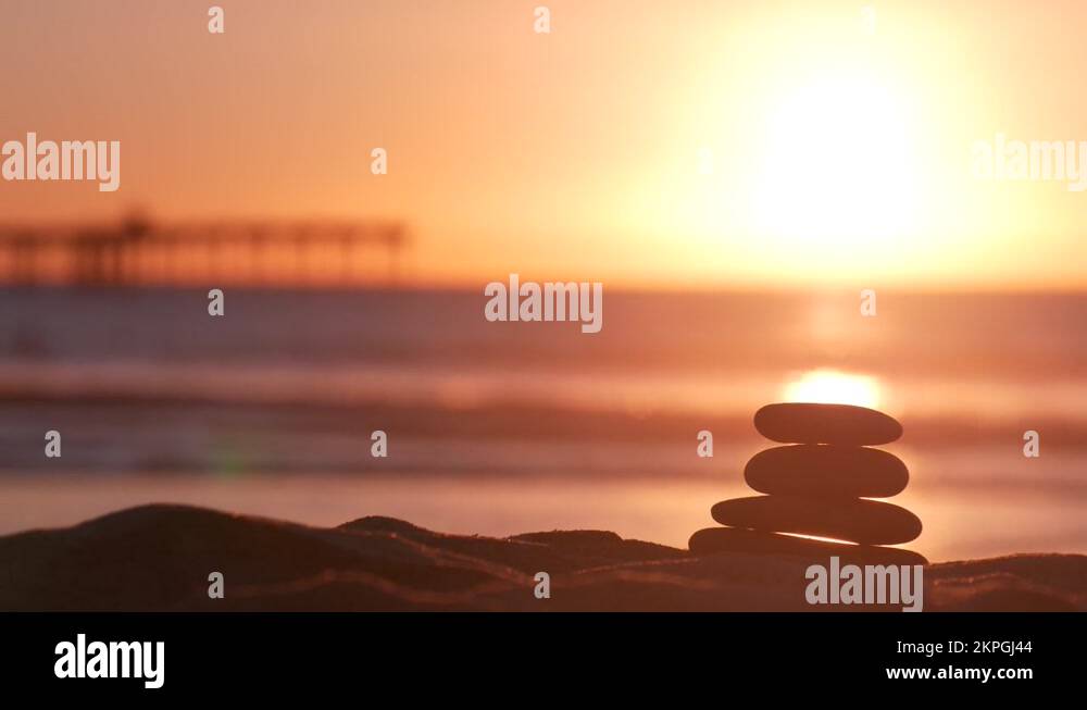 Stack of pebble stones, sandy ocean beach, sunset sky. Rock balancing ...