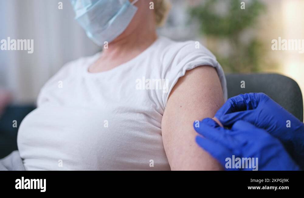 Nurse putting band-aid on senior woman's arm after vaccine injection ...