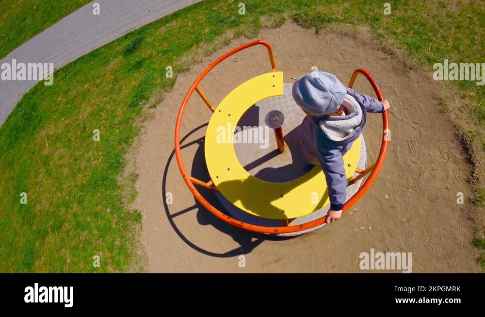 Little girl spinning on circle carousel on children playground and have ...