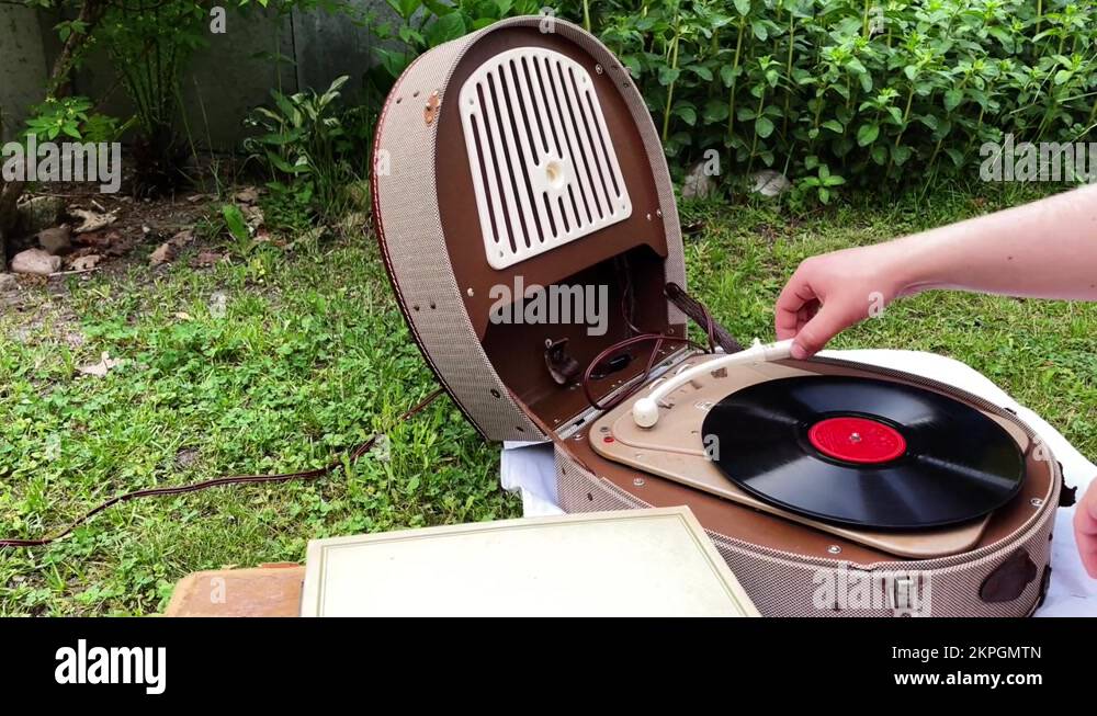An old vinyl record is put on an old vintage turntable from the 1950s ...