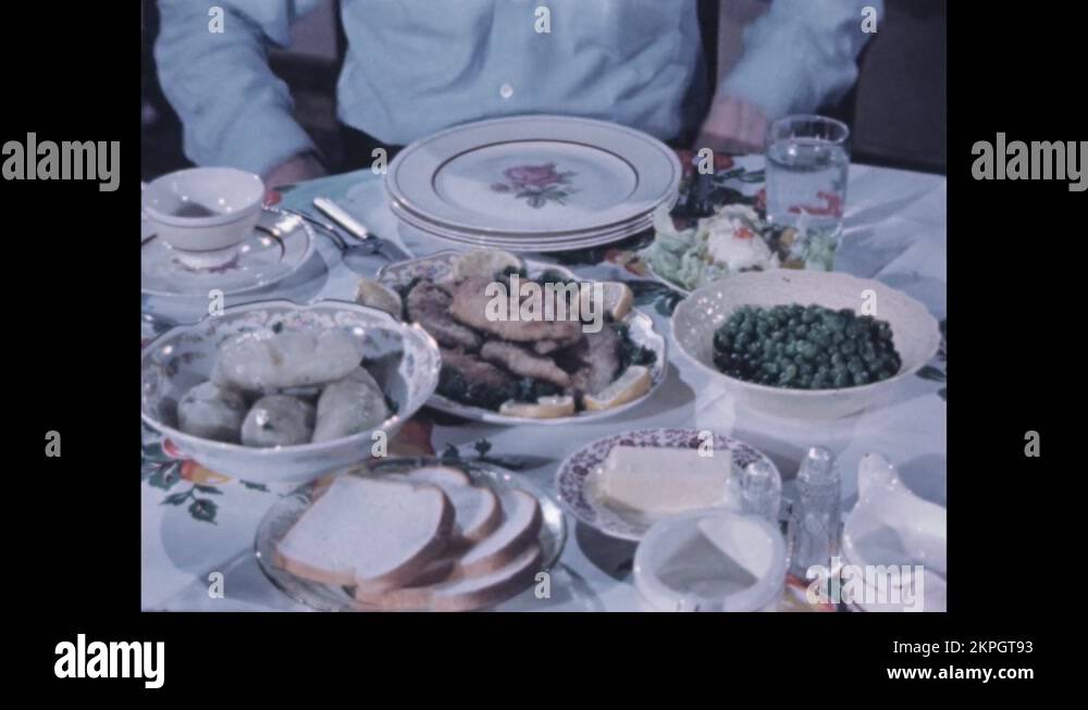 1950s: Dinner table set with meat, potatoes, lima beans and slices of ...