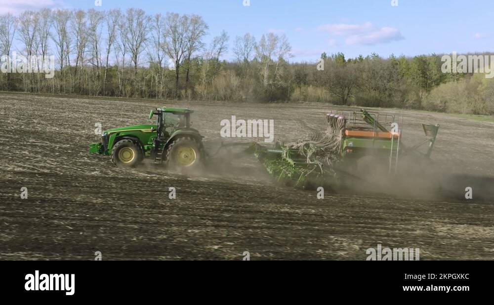 Tractor sowing seeds with seeder driller in field. Process of sowing ...
