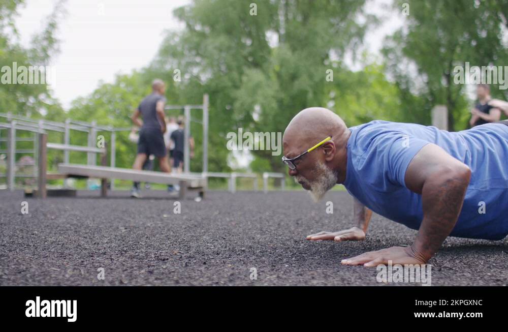Senior athletic man stretching on the ground in an outdoor gym location ...