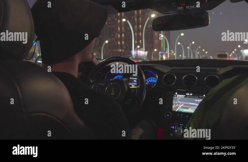Young Man Driving Luxury Car on Streets of Dubai at Night, Back View ...