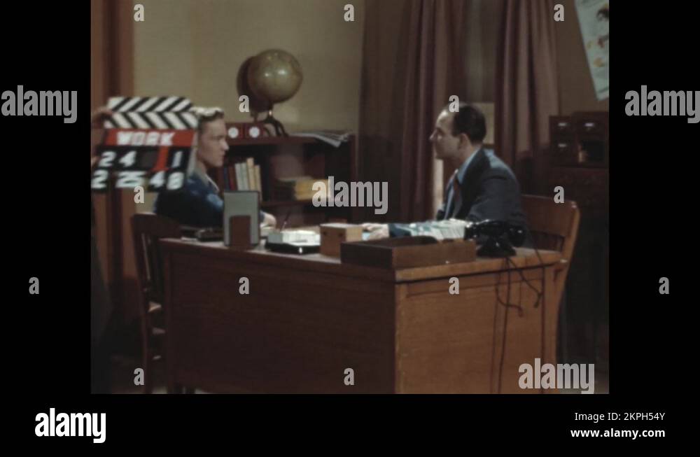 1940s: Work title on clapper board on set. Boy attends office job ...
