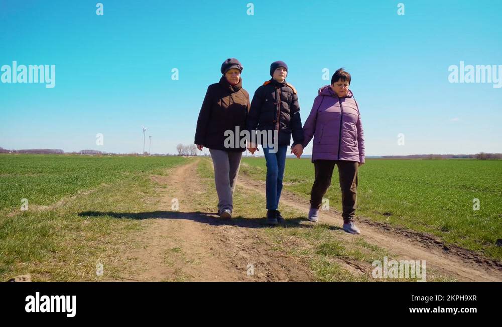 Scared refugee boy with his grandmothers holding hands and walking by ...
