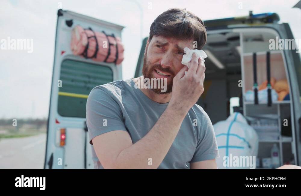 A wounded military man sitting touched his face with blood near an ...