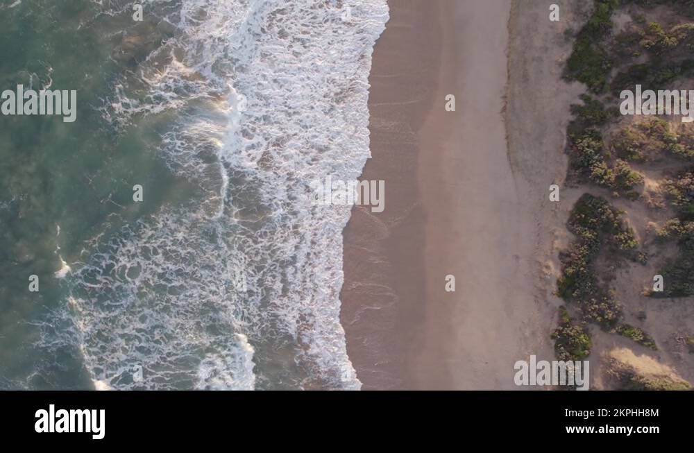 Vertical slow moving drone footage of waves hitting the beach at Point ...