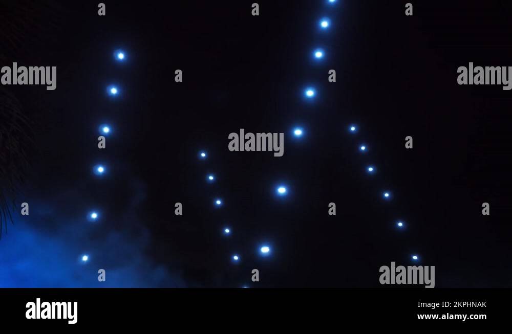 Bright colored lights move in rows in the dark night sky. Drone show ...