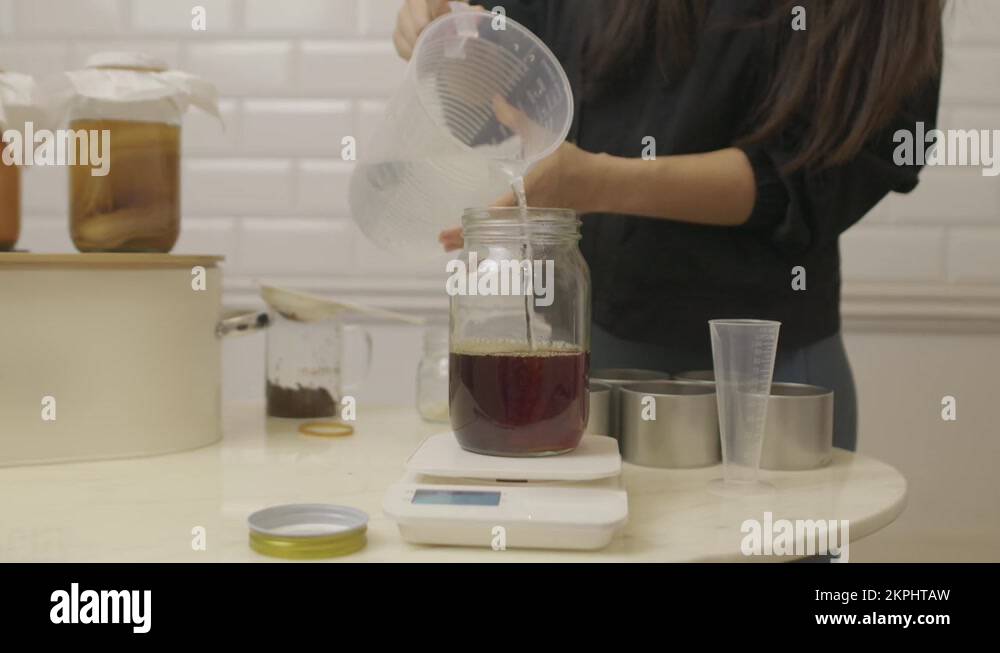 Woman adds water inside the barrel with infused tea on top of digital ...