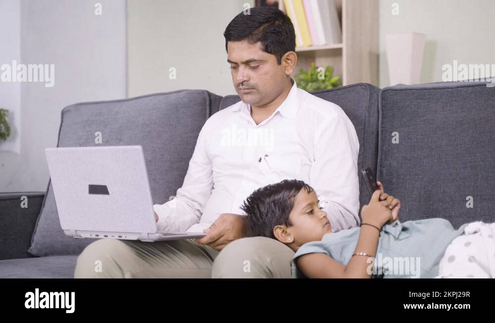 Father working on laptop while kid using mobile phone by sleeping on ...