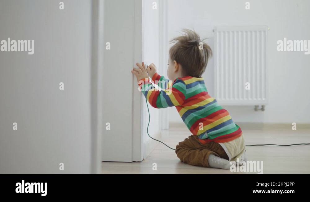 Little child connecting the electrical device plugging it into the wall ...