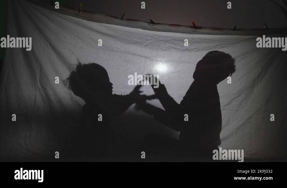 Children playing shadows on sheet tent lit by lamp in their room Stock ...