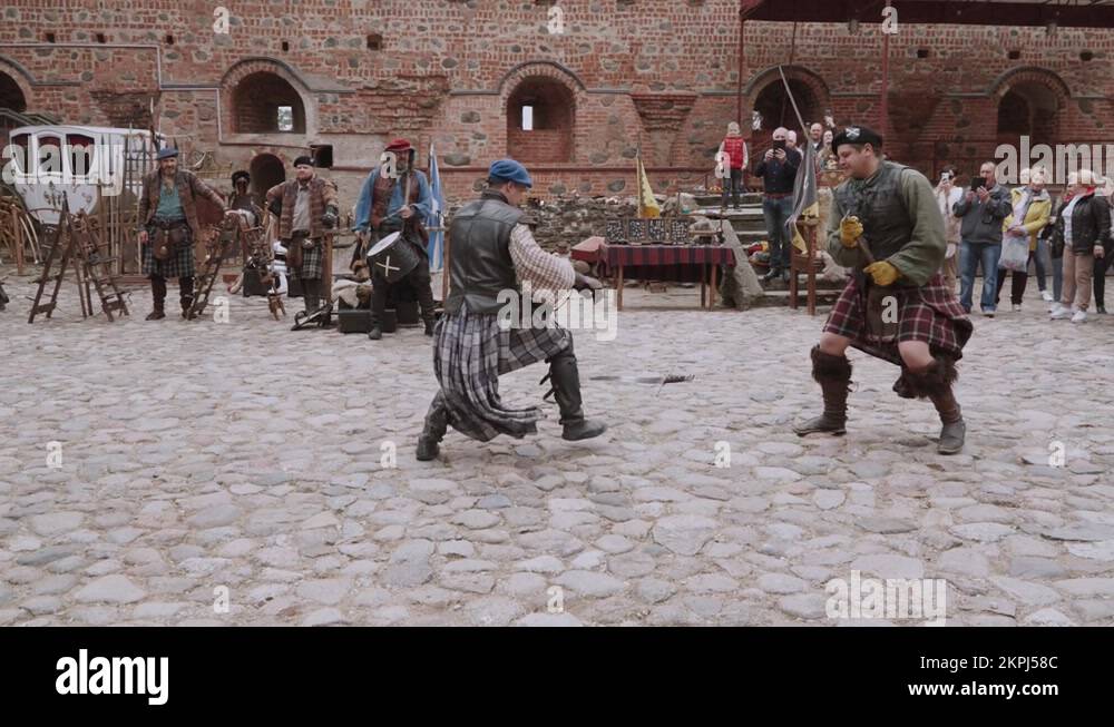 Scottish warriors in kilts fight with swords in castle yard, slow ...